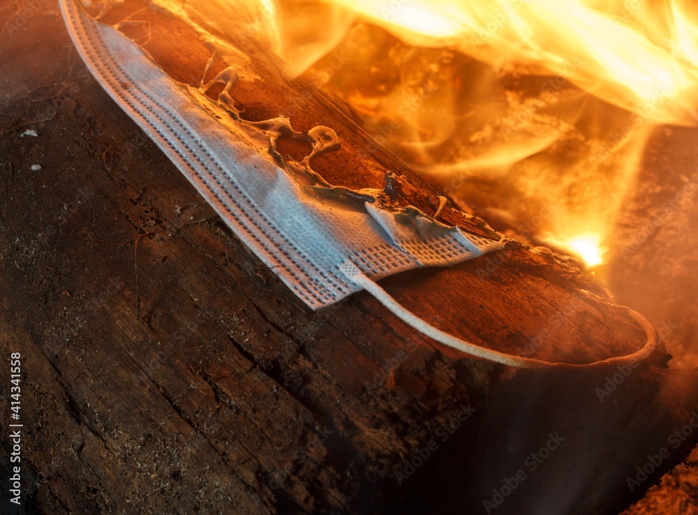 surgical mask burning on top of a log with fire, concept of ending ...