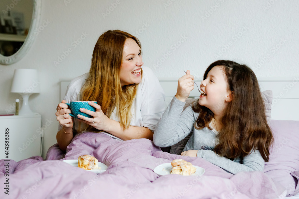 Foto de Lovely young mother and cute school kid girl cuddling together ...
