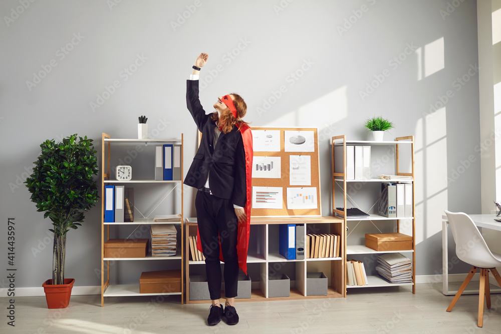 Aspiring male worker in business suit and super hero cape standing in ...
