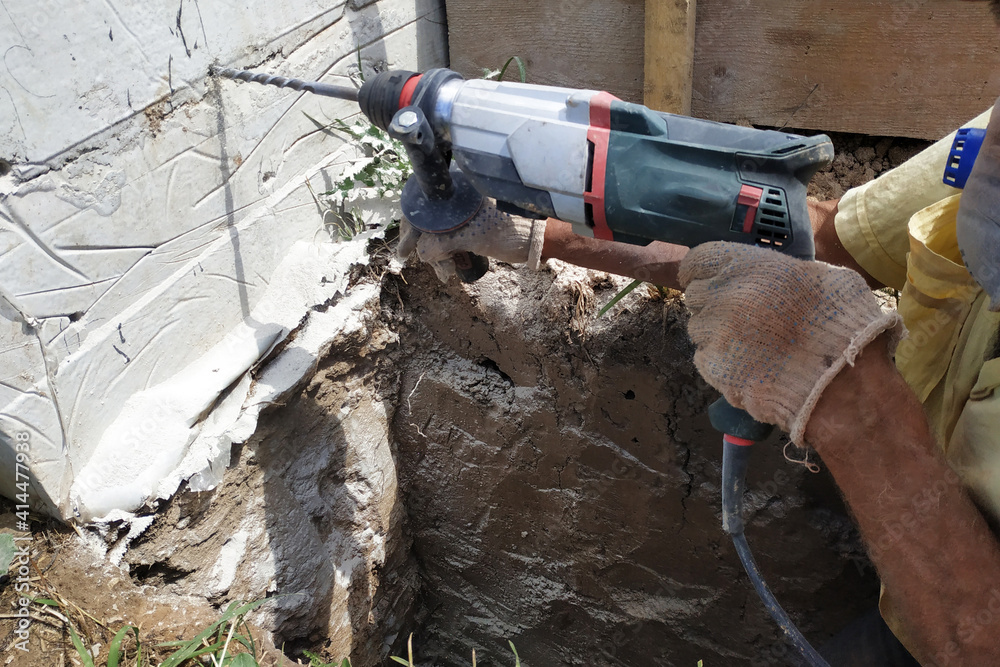 Drilling a hole in the concrete wall with a jackhammer, perforator in ...