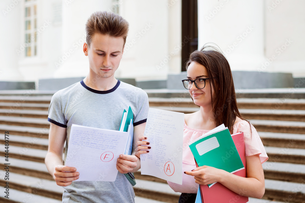 Foto de Two students, holding sheets of paper with test results. Boy is ...