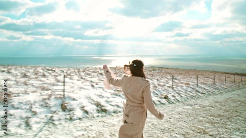 A young girl flashing, waving her scarf on a windy day at the seashore ...