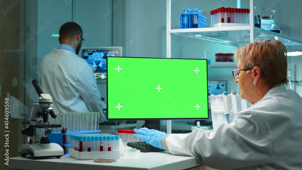 Senior doctor working at computer with green screen in modern equipped ...