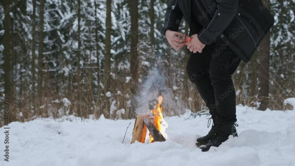 Man enjoys the fire at camping in the winter woods, making a fire ...