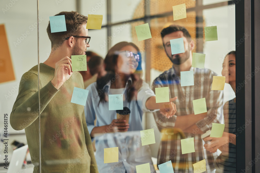 Smart and talented young people putting sticky notes on wall Stock ...