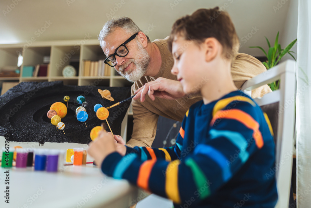 Happy school boy and his father making a solar system for a school ...
