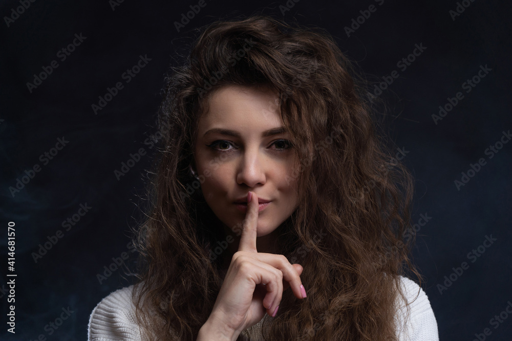 Pretty woman making silence sign with copy space on black background ...