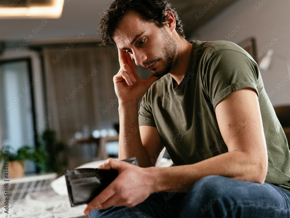 Young man checking empty wallet, no money. Unemployed sad man sitting ...