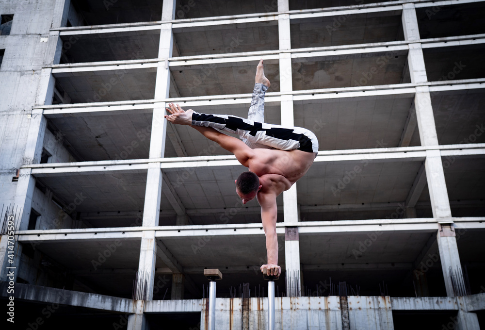Circus artist keeps balance on one hand in the industrial concrete ...