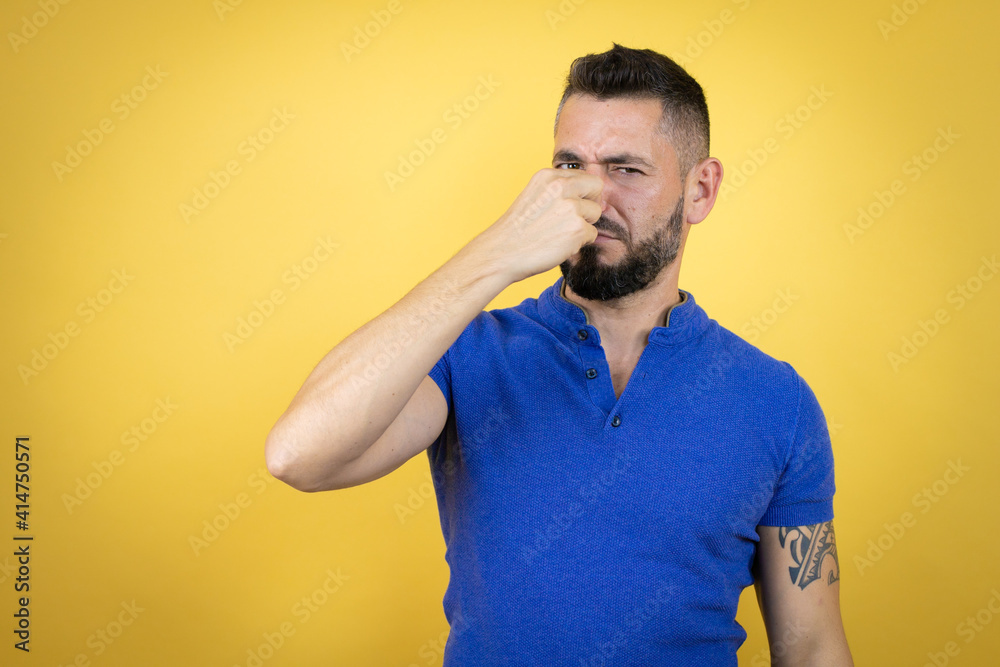 Handsome man with beard wearing blue polo shirt over yellow background ...