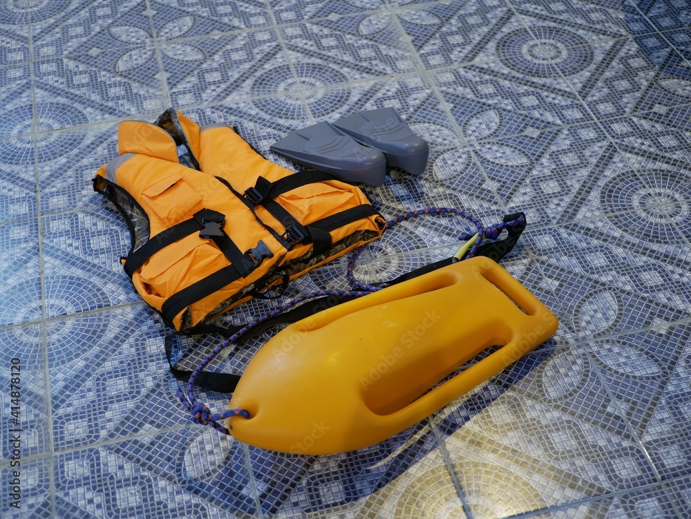An orange life jacket, gray small rubber flippers, and an orange ...
