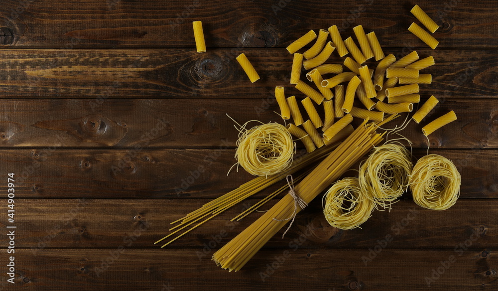 Spaghetti, egg pasta and tortiglioni macaroni on wooden plank table ...