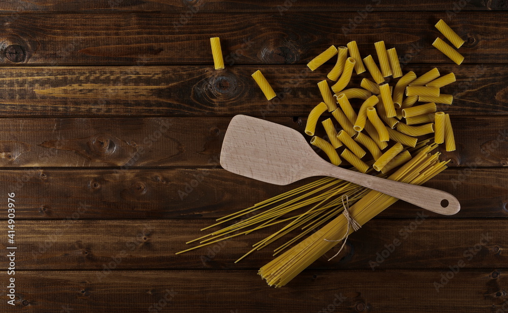 Spaghetti bundle and tortiglioni pasta pile with spatula spoon on ...