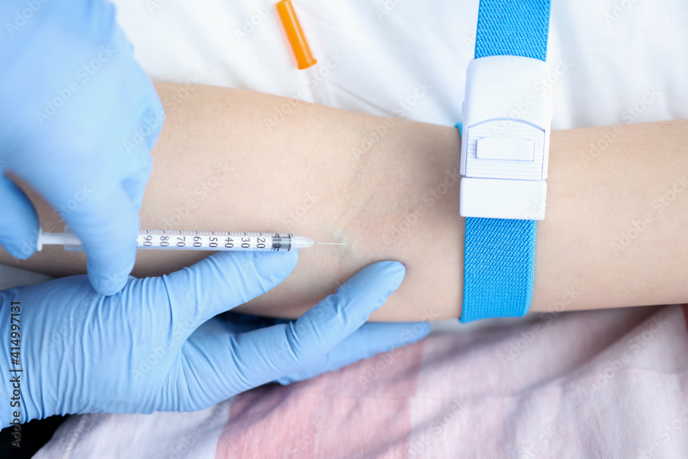 Nurse giving intravenous injection of medication to patient closeup ...