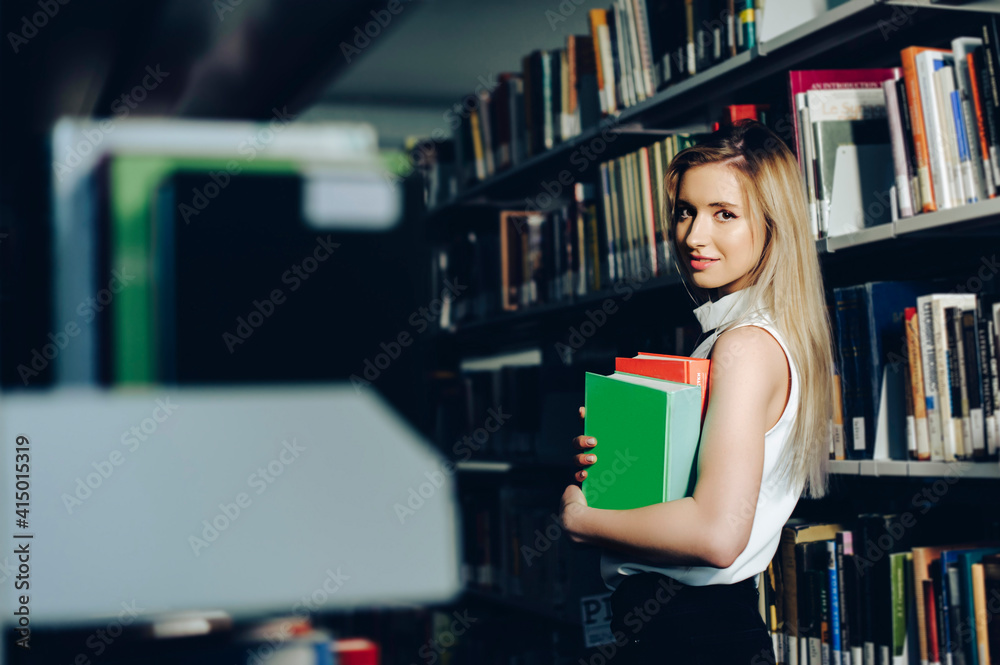 Beautiful girl student reads books in a library on the window sill ...