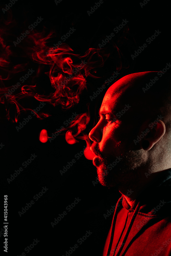Side view of male rocker with bald head smoking and exhaling fume in ...
