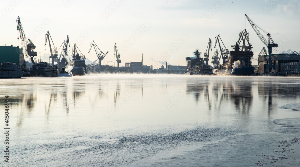Cranes of of the Baltic shipyard on a frosty winter day, steam over the ...