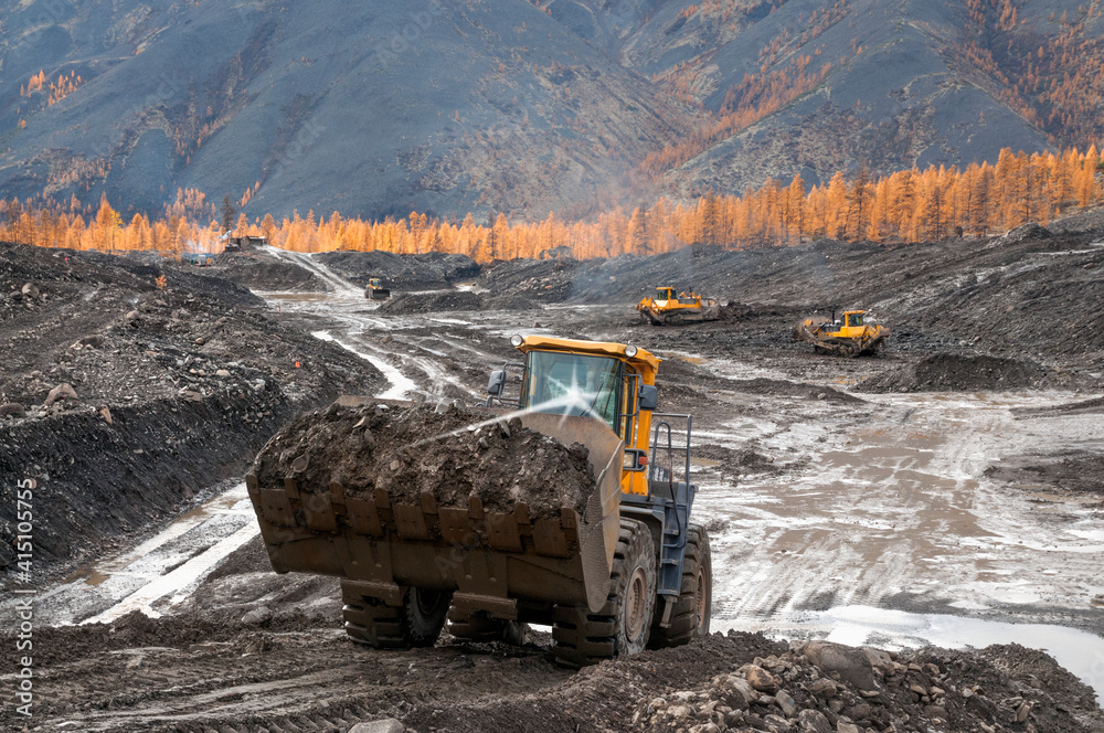 Wheel loaders and bulldozers in operation in an industrial mountainous ...