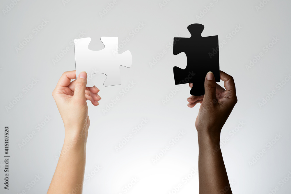 Hands of people of different nationalities hold puzzle pieces. Symbol ...
