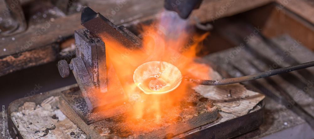 Melting process of precious metal gold behind a jeweler's workbench ...