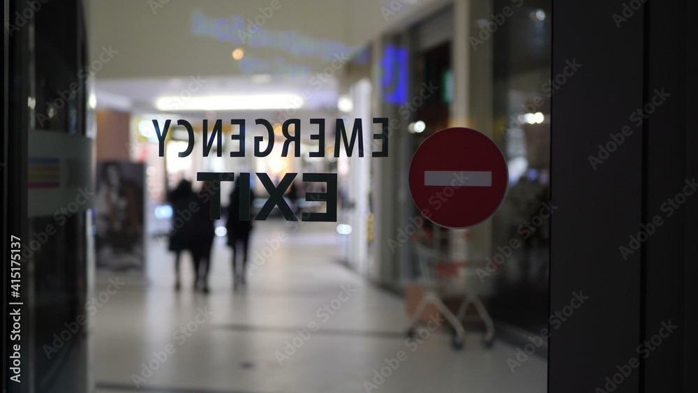 Emergency exit sign on empty city mall during pandemic Stock Photo ...
