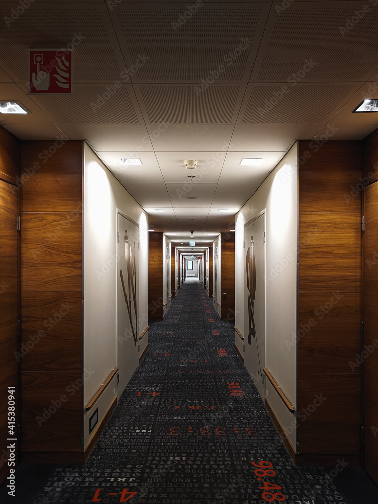 Long corridor hallway in a luxury hotel. Dark textured carpet on the ...