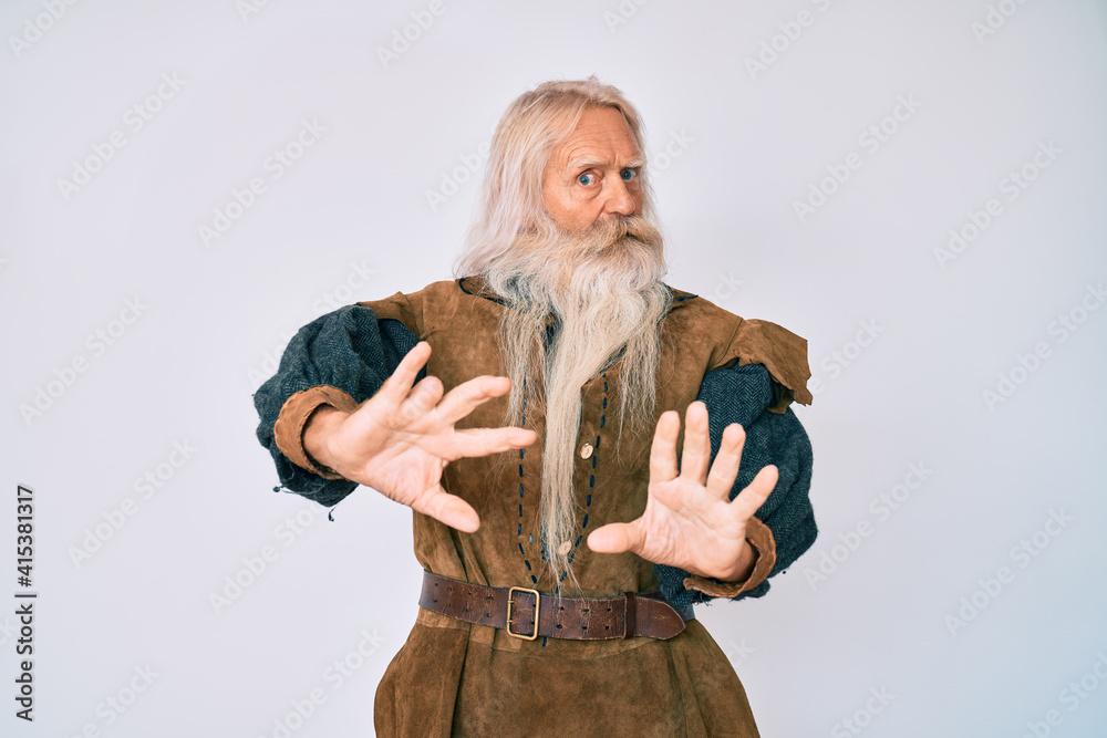 Old senior man with grey hair and long beard wearing viking traditional ...