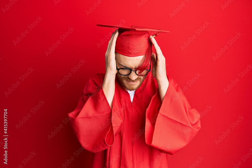 Young redhead man wearing red graduation cap and ceremony robe ...
