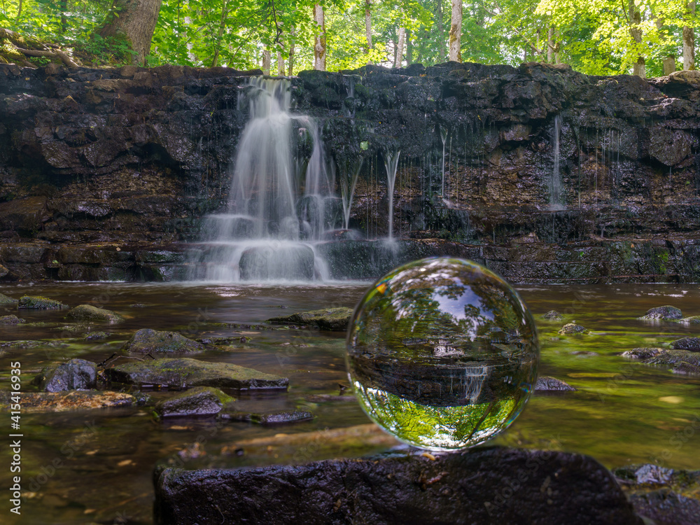 Front view of Ivande waterfall with a glass ball in the foreground ...