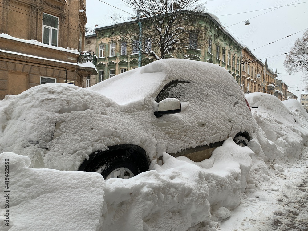 The car was covered with snow in the parking lot. Cars under a large ...