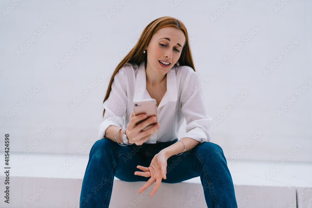 Puzzled female blogger 20s checking sms message on mobile gadget ...