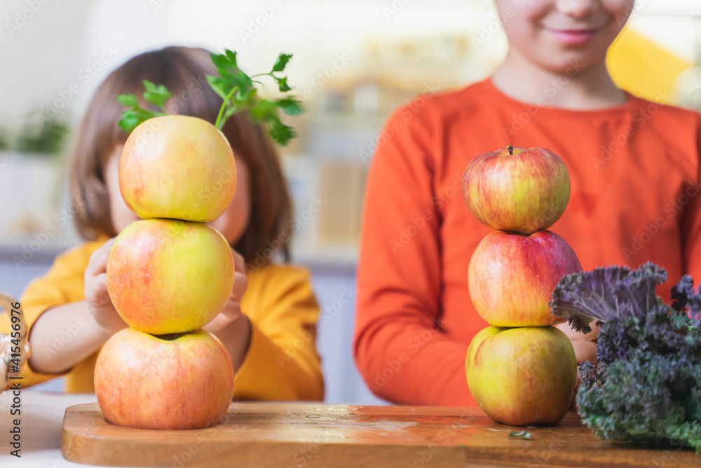 Funny kids building pyramid of apples in kitchen, crazy having fun ...