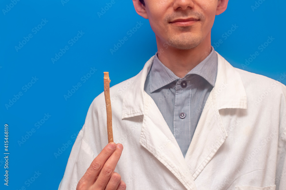 A young man holds a miswak (siwak) in a white coat. arak tree ...
