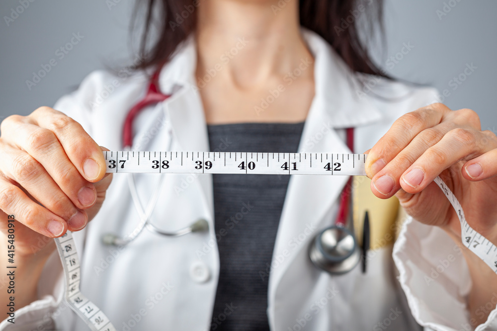 Close up isolated image of a caucasian doctor holding a tape measure in ...