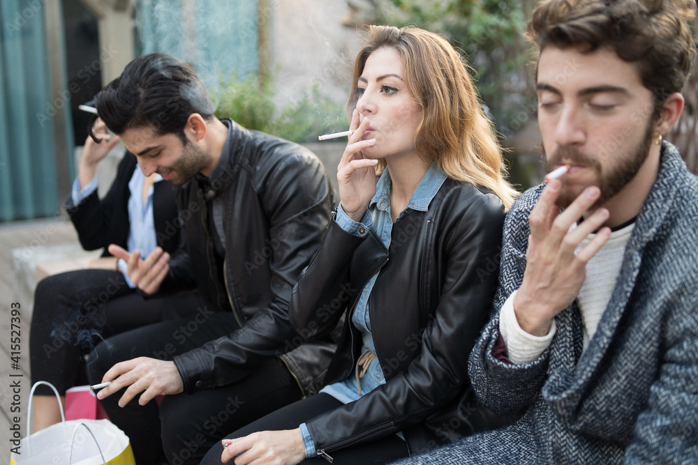 Bad habits - group of young friends smoking cigarettes together ...