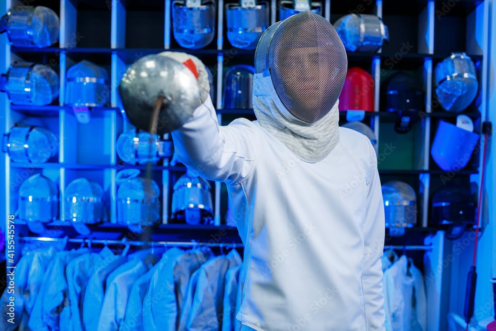 Young guy in a fencing suit with a sword in his hand, on a blue ...
