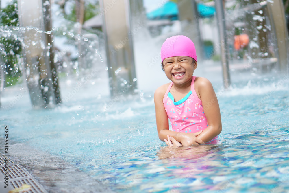 Asian child cute or kid girl wearing swimsuit with cap on swimming pool ...