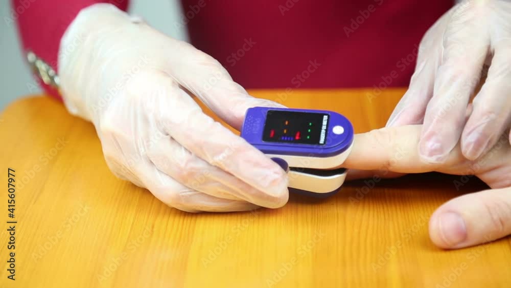Oximeter on the finger of a woman's hand, reading oxygen in human blood ...
