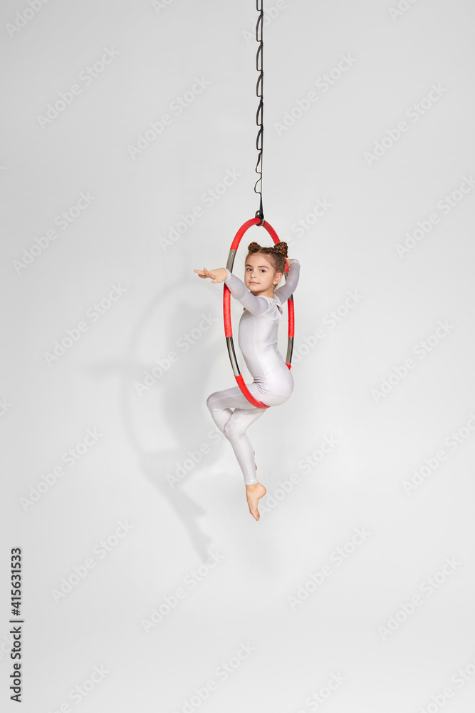Elegant little child girl gymnast shows an acrobatic performance on an ...