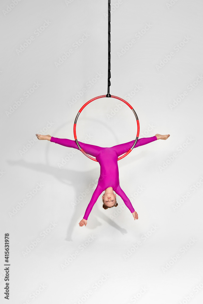little child girl gymnast in pink sportwear shows an acrobatic ...