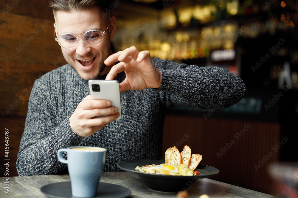 Beautiful smiling male in cafe drink coffee and eating salad. Young man ...
