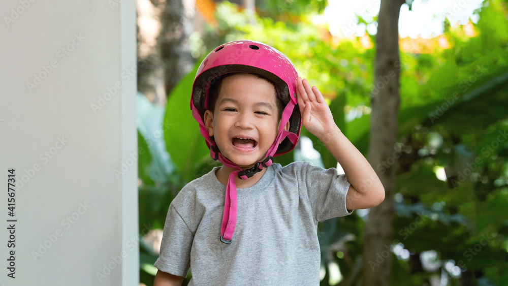 Asian 4 years old boy with pink helmet making salutation to camera ...