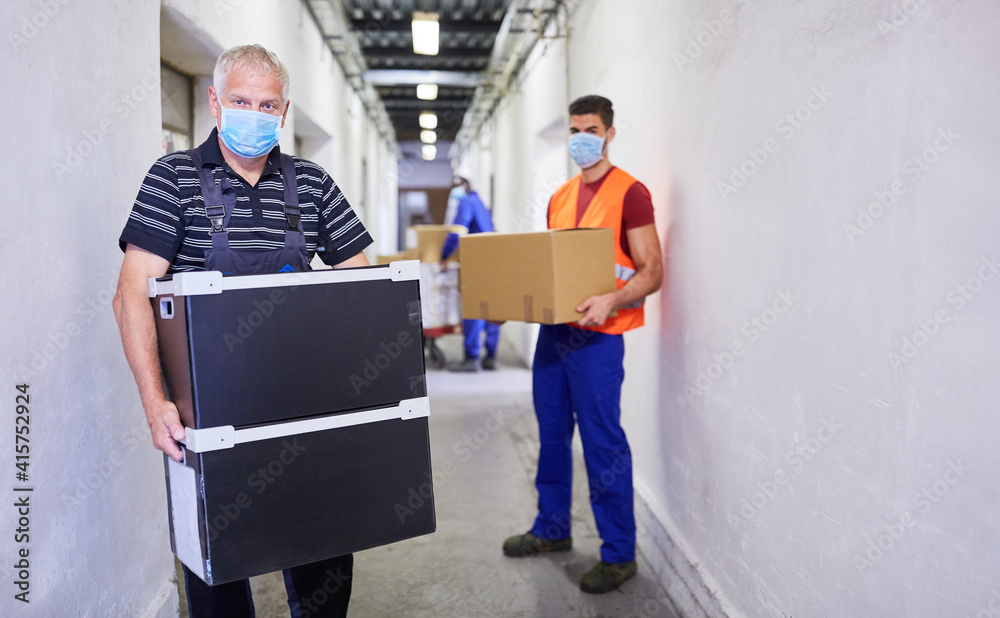 Workers with masks because of Covid-19 carry packages Stock Photo ...