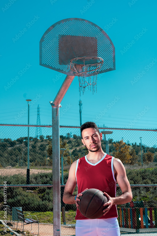 young white man posing on a basketball court while catching a ball ...
