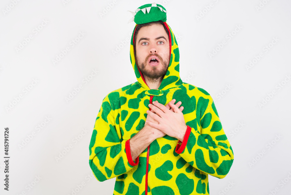 Scared young caucasian man wearing a pajama standing against white wall ...