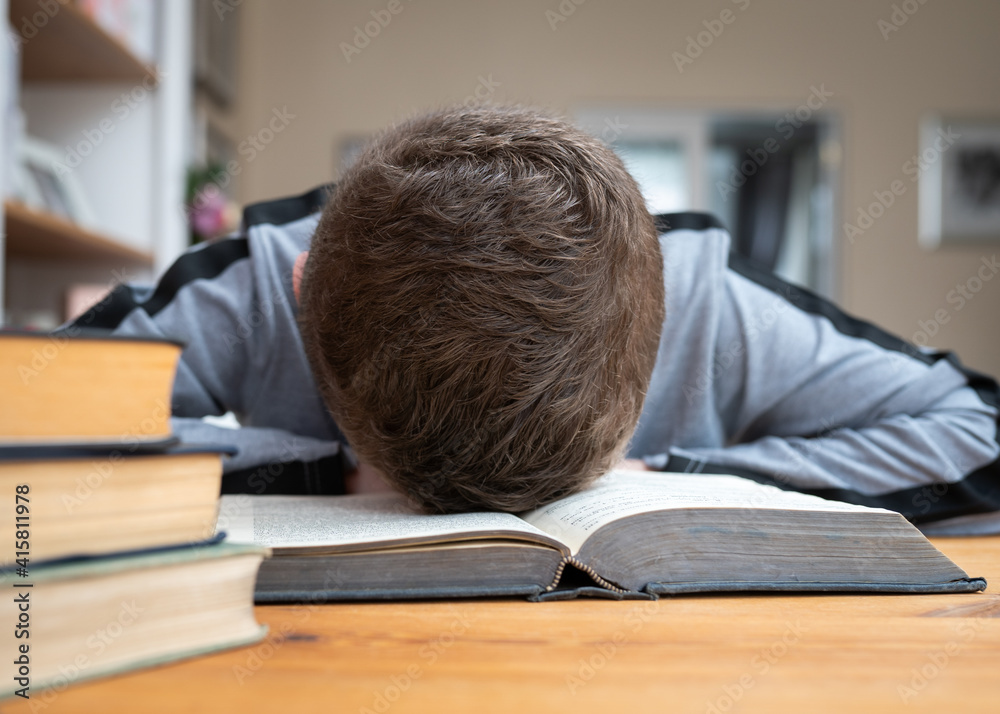 Cute intelligent young boy tired from reading big old story book at ...