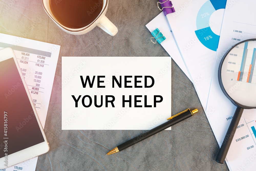 WE NEED YOUR HELP is written in a document on the office desk, coffee ...