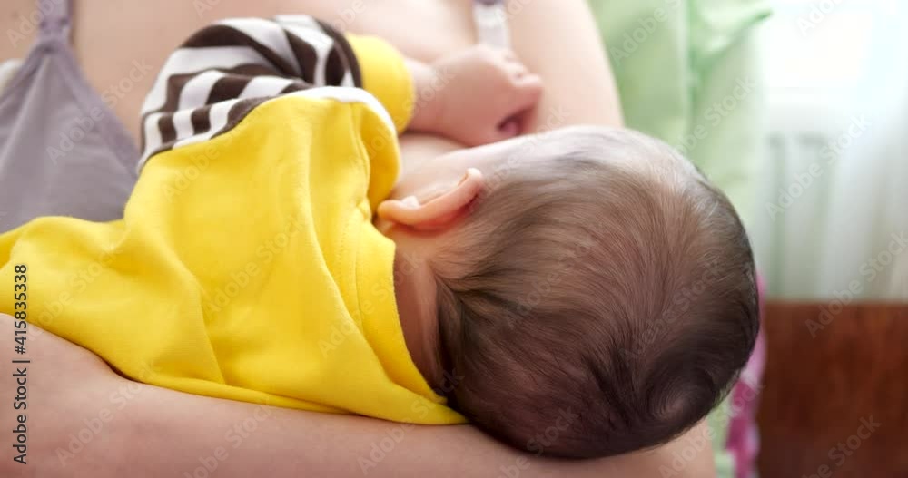 Mother breastfeeding her newborn baby on sofa. Milk from mother's ...