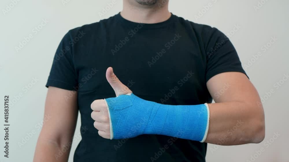 Unrecognizable man in a black T-shirt shows thumbs up and hand wrapped ...