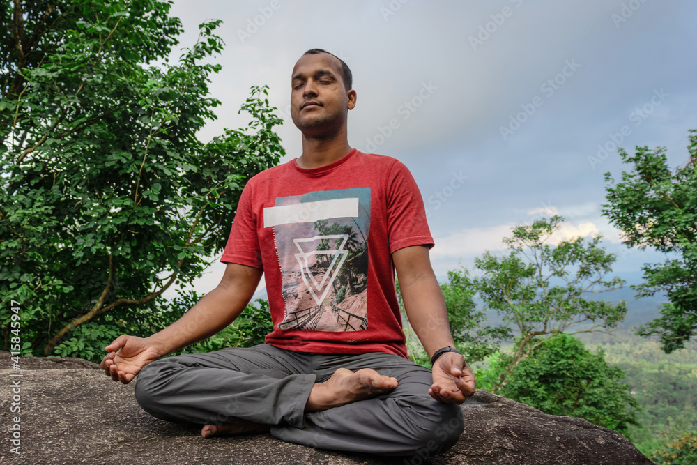 man meditating at rock in deep green forests for spiritual ...